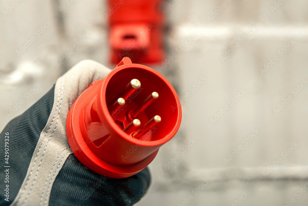 High voltage plug in hand. Connecting a 380 volt high voltage, three ...