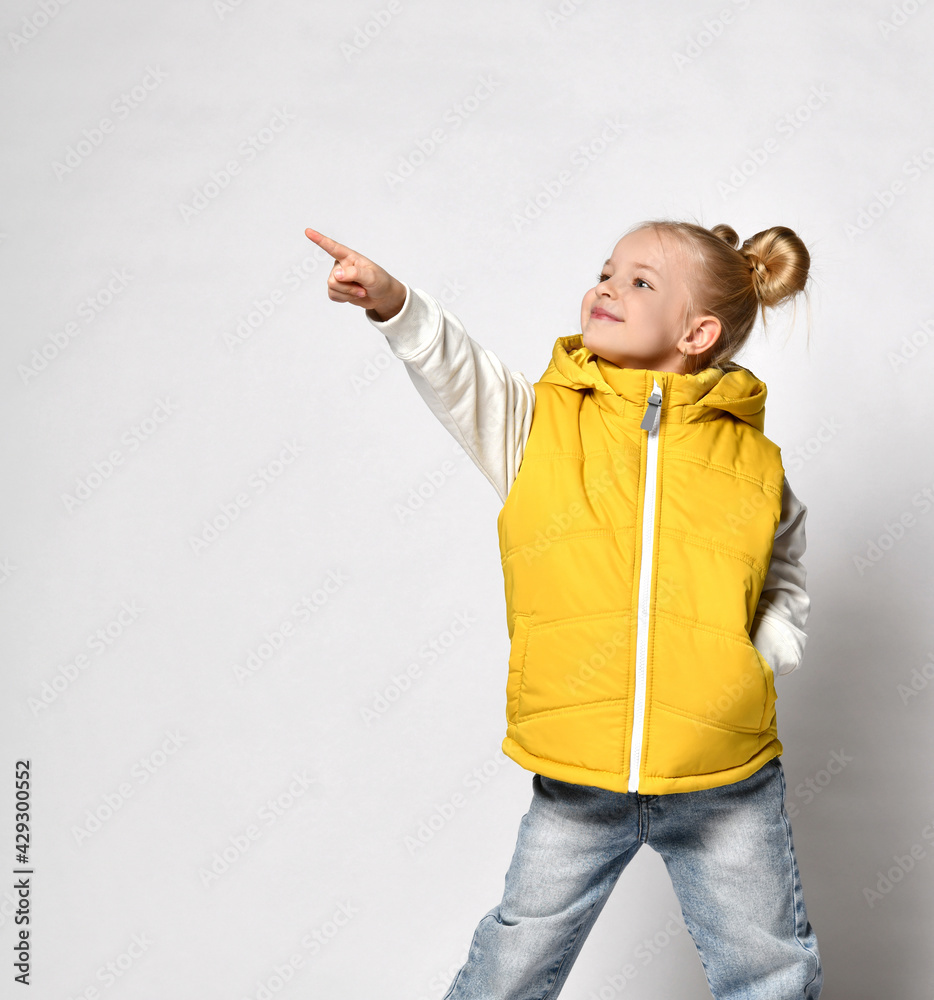 pretty smiling blonde girl in a yellow puffy vest is standing with her ...
