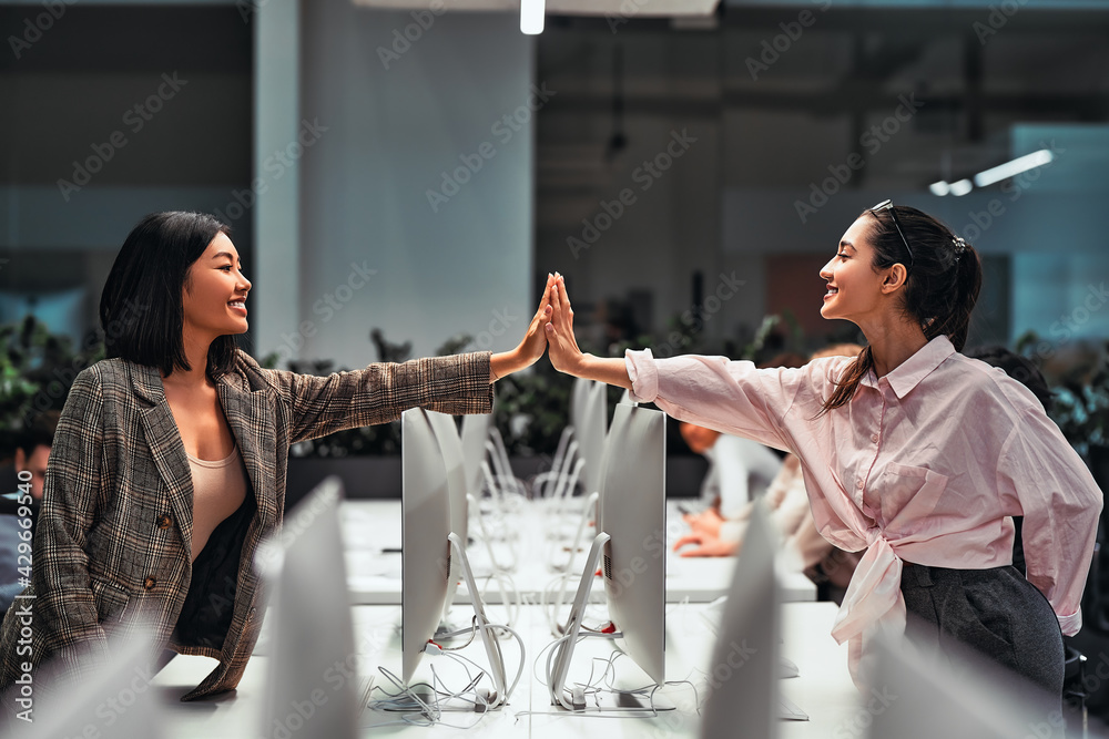 We work together as a team. Two beautiful business women give each ...