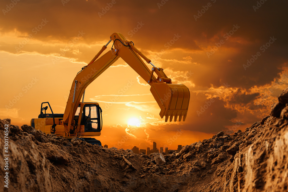 Excavators are digging the soil in the construction site on the sunset ...