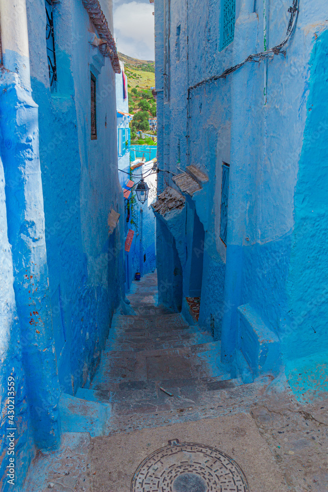 Narrow empty winding lane with steps in the blue medina of the ...