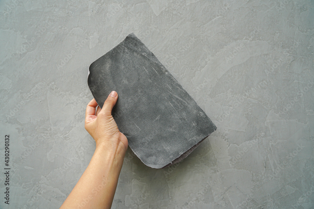 close up worker hand use sandpaper sheet for smooth cement wall texture Stock Photo Adobe Stock