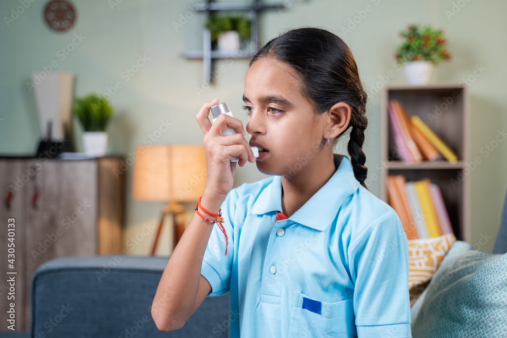 Side view young girl kid using asthma medication inhaler after taking ...