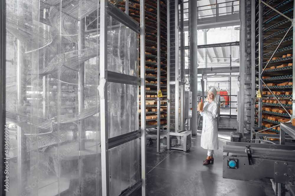 Baker woman holding fresh bread in hands on background automatic ...
