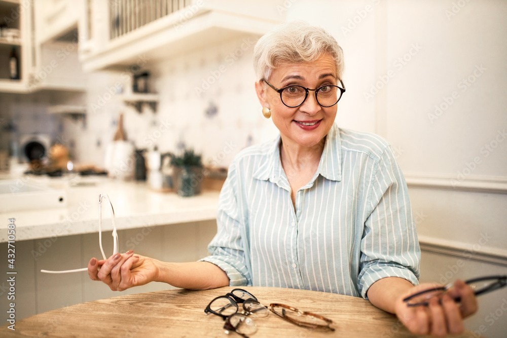 Indoor image of emotional retired woman with short gray hair sitting at ...