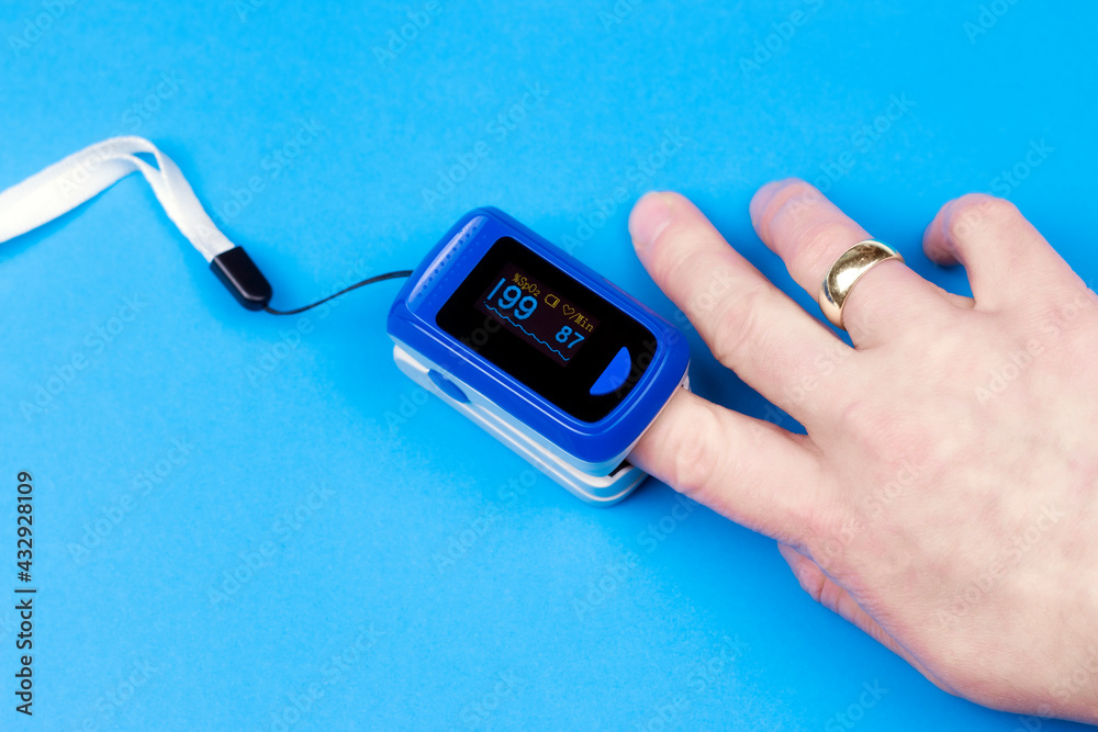 Pulse oximetry on the finger with blue background. Pulse oximetry a ...