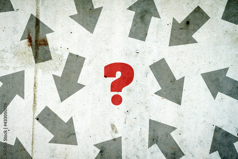 Arrows in different directions on a concrete wall. Red question mark ...