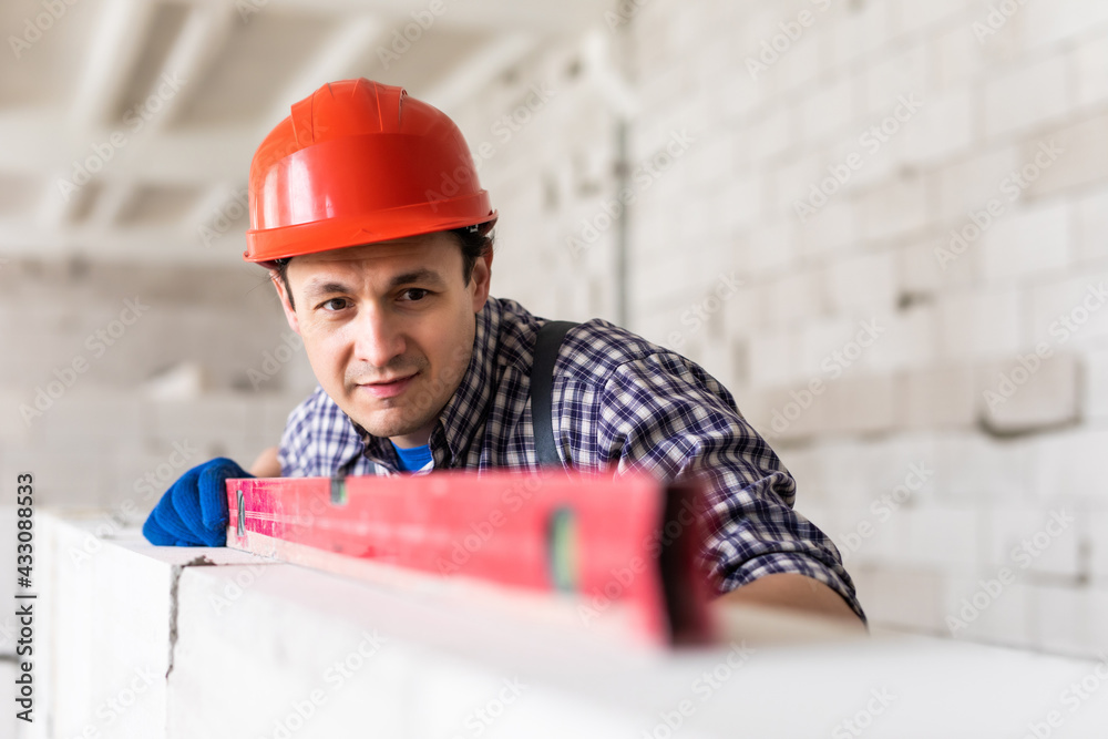 Worker using water level meter measuring the wall builder working with ...