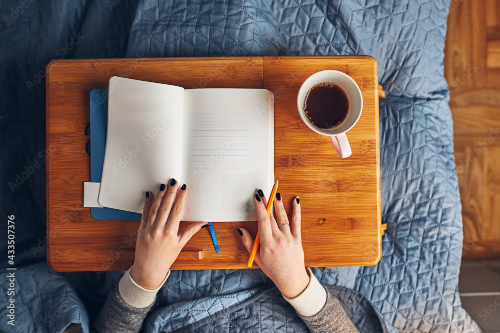 Student learning at home. Young woman making notes, reading and ...