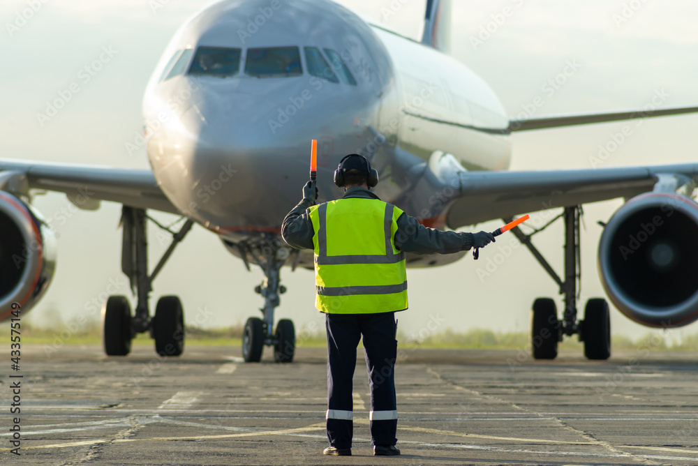 Ground Crew Signaling To Airplane On Wet Runway Stock Photo | Adobe Stock