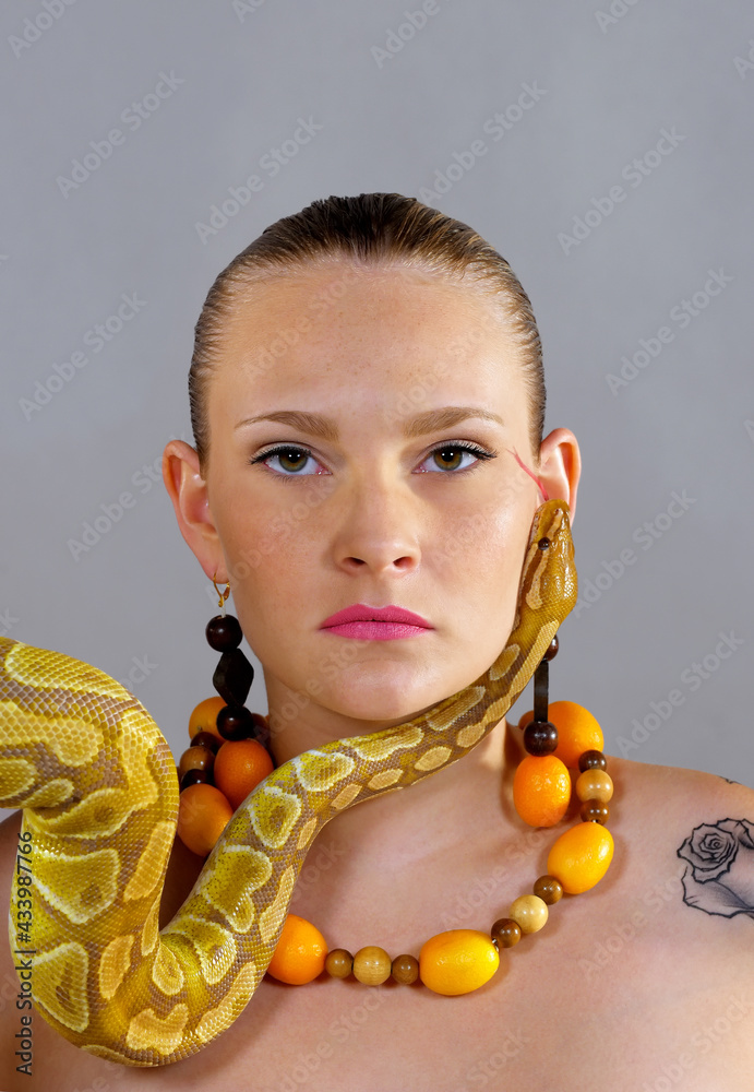 A beautiful young woman poses nude for the camera. Her earrings and ...