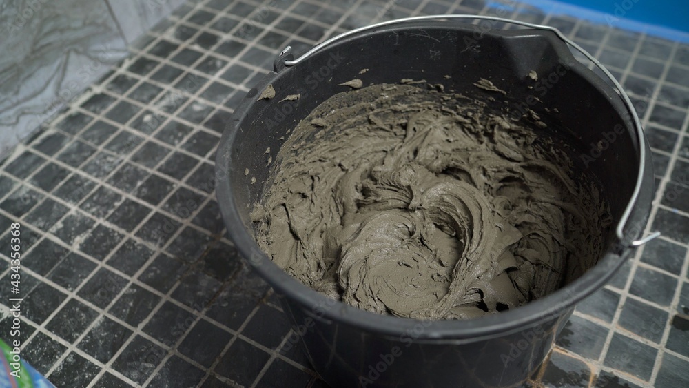 A person mixes cement and water in a container to get the finished ...