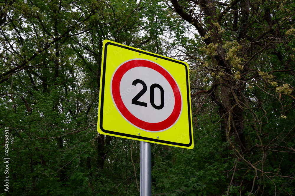 yellow red colour 20 km speed limit traffic sign at the edge of a ...