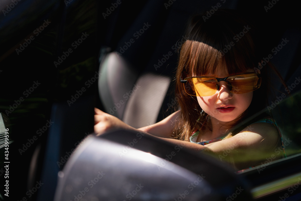 Dangers and risks of underage driving. A little child girl panic in the ...