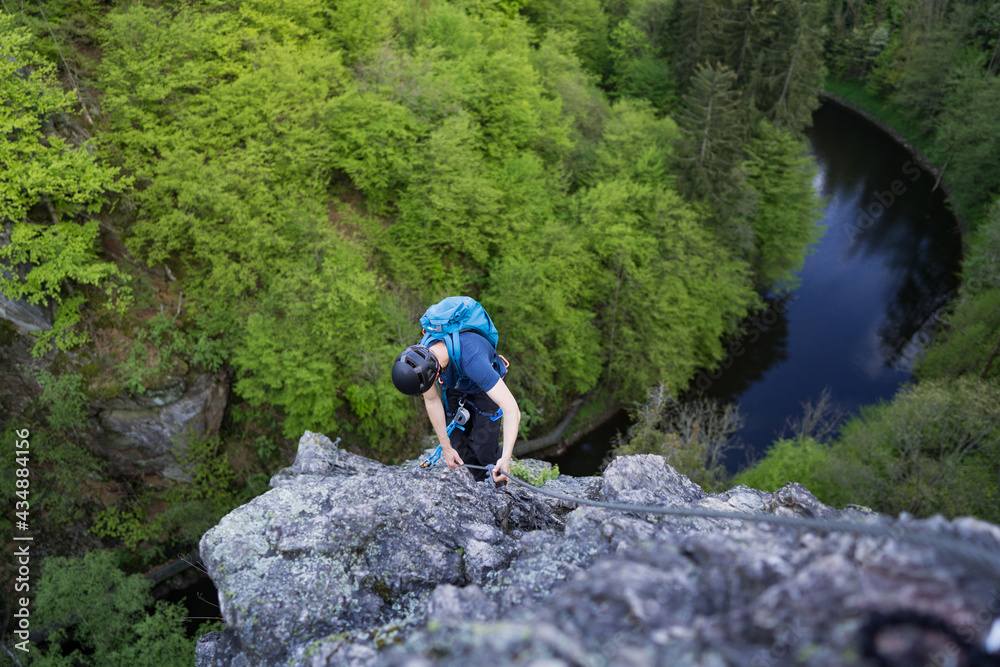 Alpine ferrata ascent to a peak or summit. Male climber equipped with ...
