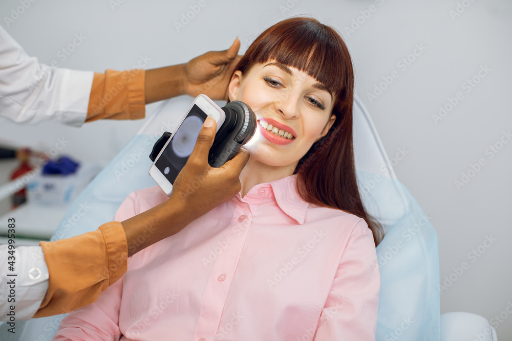 Smiling young Caucasian woman having appointment with her doctor ...