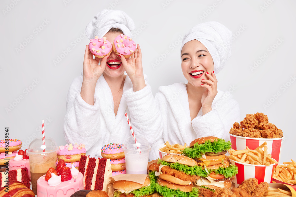 Junk food and unhealthy lifestyle concept. Funny young women spend free ...