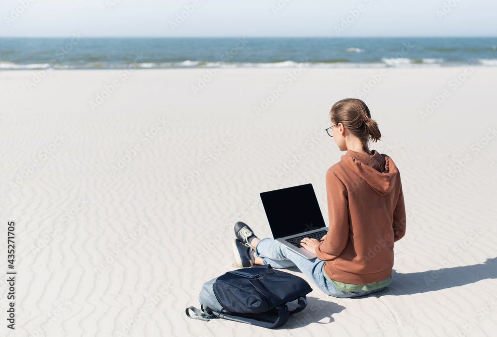 Woman using laptop computer on a beach. Freelance work, vacations ...