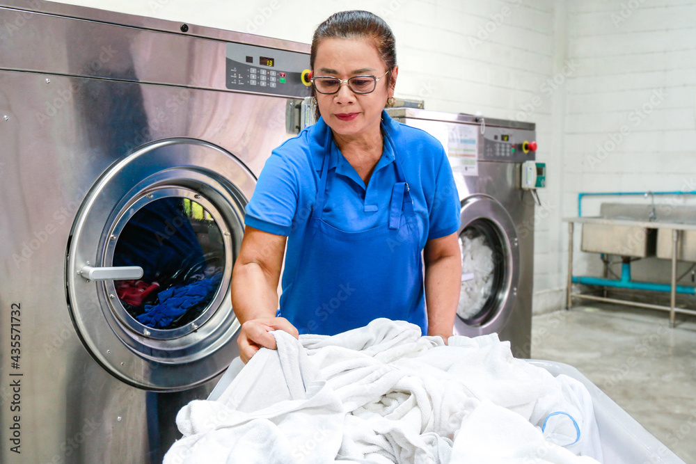 Stock-Foto „A laundry staff wearing a blue uniform is checking towels ...