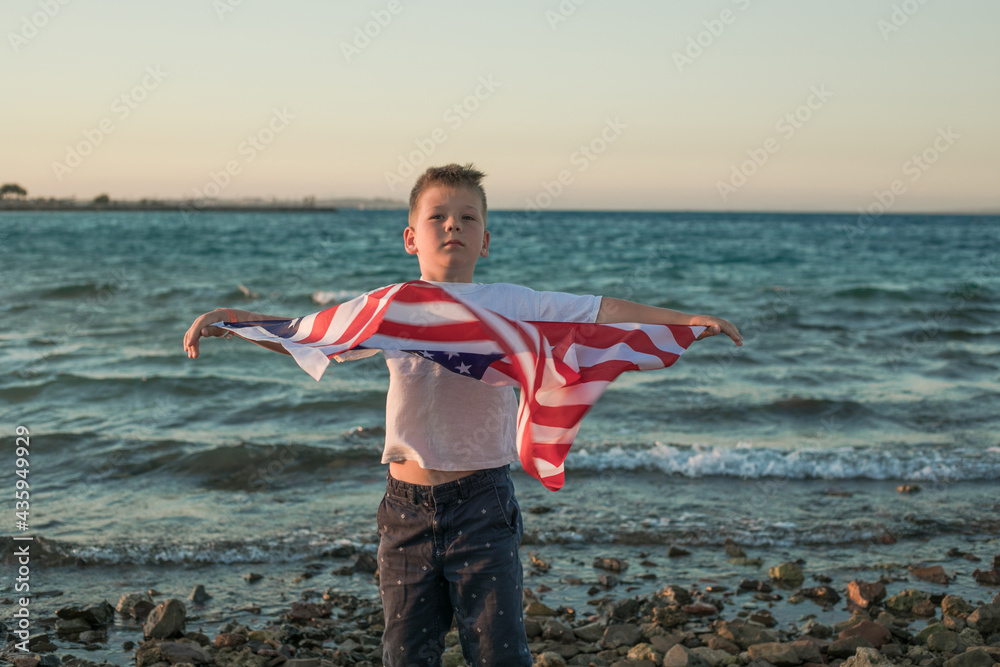 Little boy lets the american flag fly in his hands on the wind at the ...