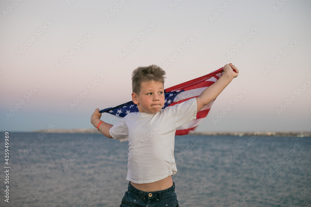 Little boy lets the american flag fly in his hands on the wind at the ...