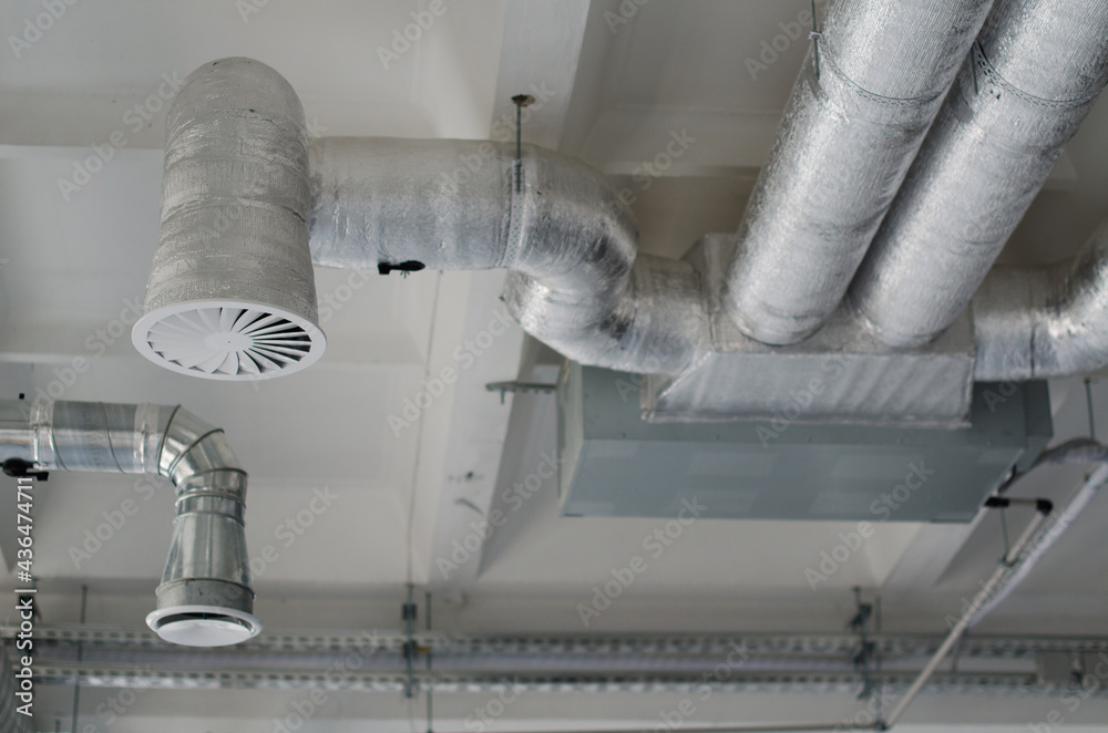 Ventilation pipes in silver insulation material hanging from the ...