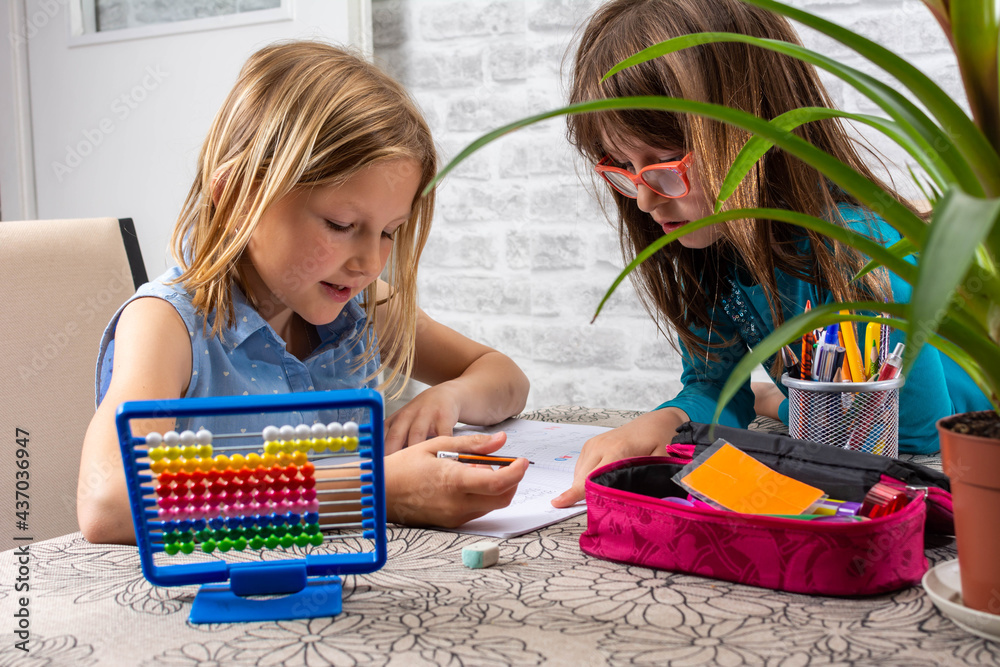 Happy sister helps her sister to do their homework. Two cute little ...