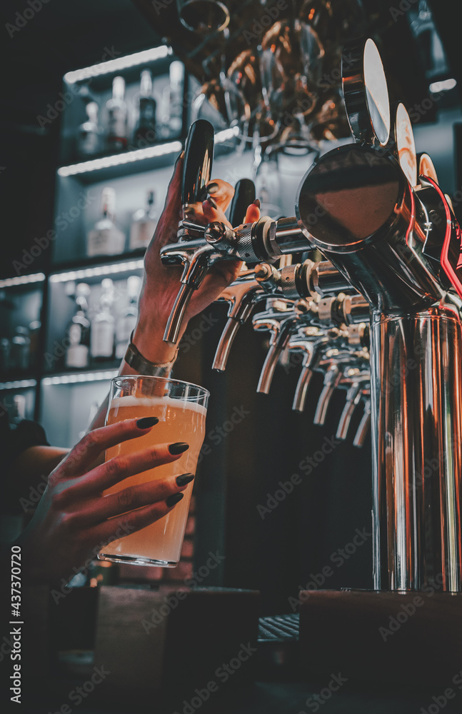 Foto de Stock bartender hand at beer tap pouring a draught beer in glass serving in a restaurant ...
