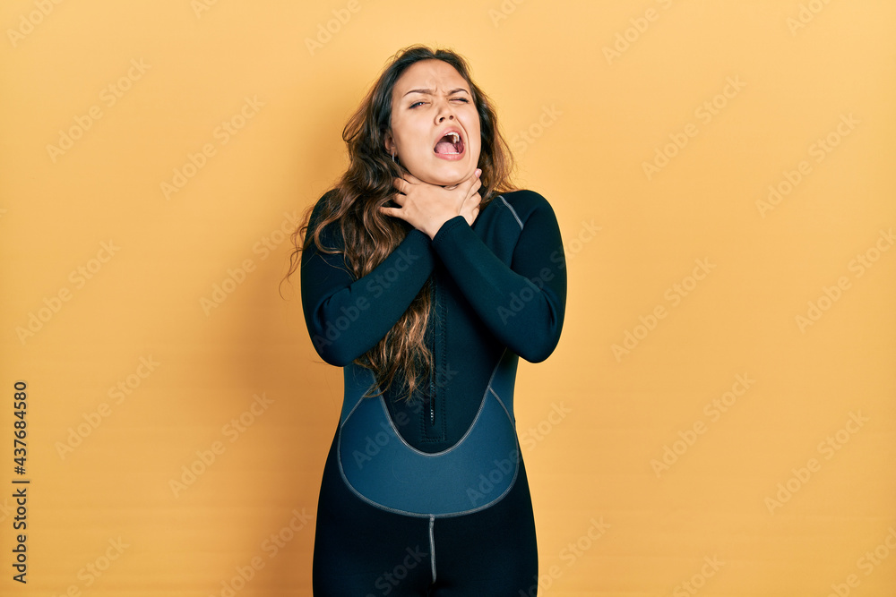 Young hispanic girl wearing diver neoprene uniform shouting suffocate ...