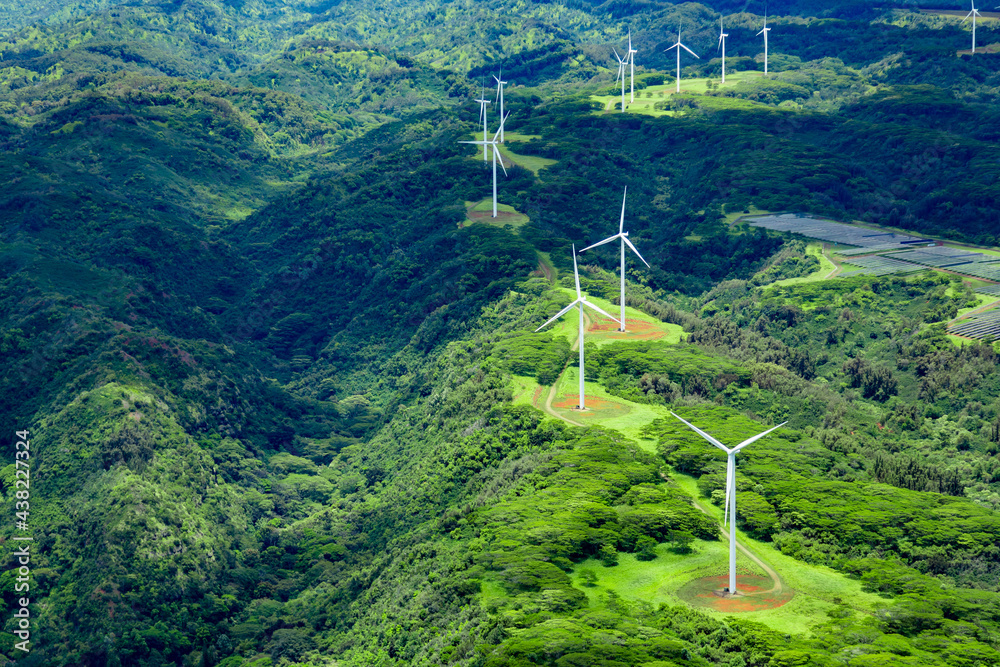 Aerial photo of white windmills in a line on green land leading off ...
