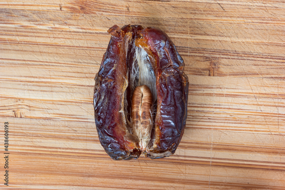 Big pitted dried opened date with visible seen inside set on a wooden ...