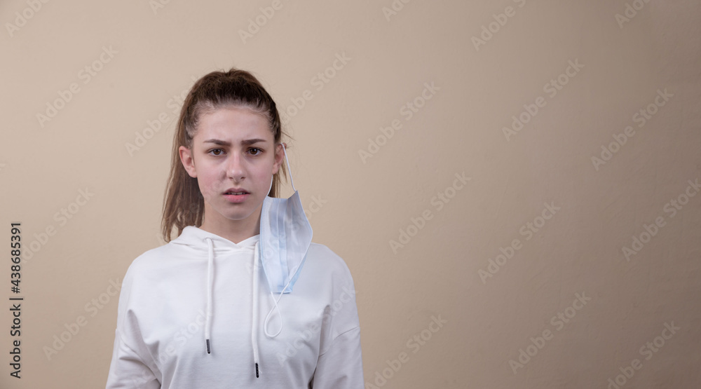 Sad, beautiful young brunette girl with the mask removed on her ears ...