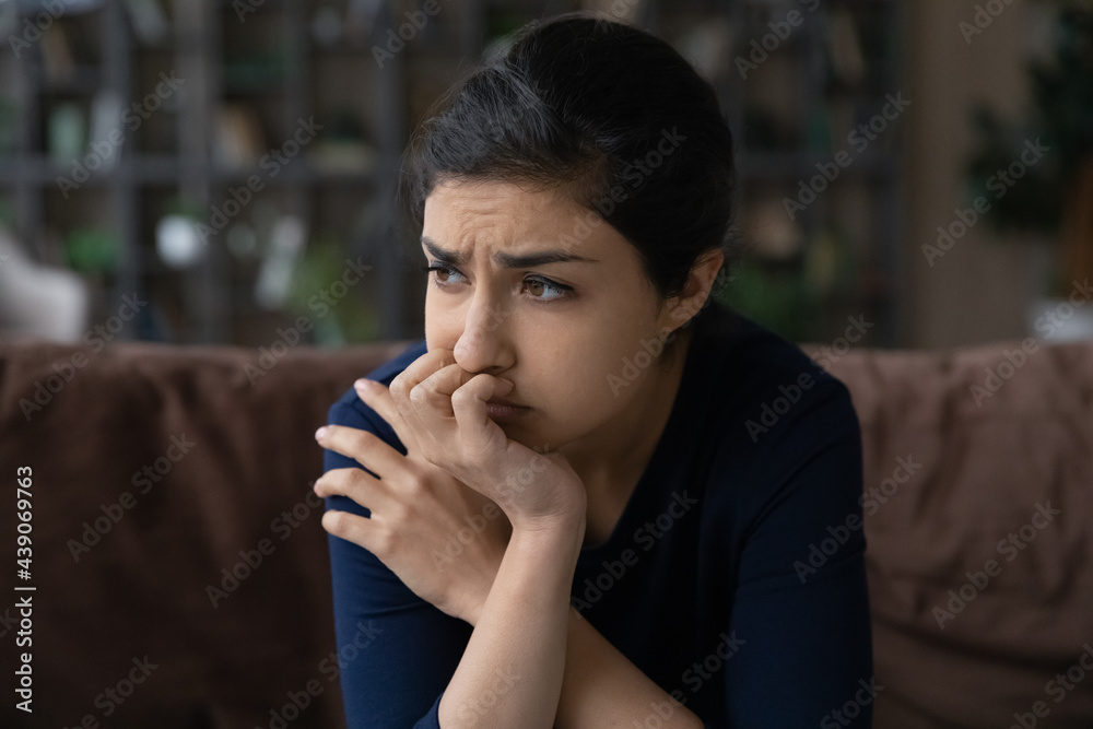 Pessimistic view. Confused indian woman sit on couch with sad look hurt ...