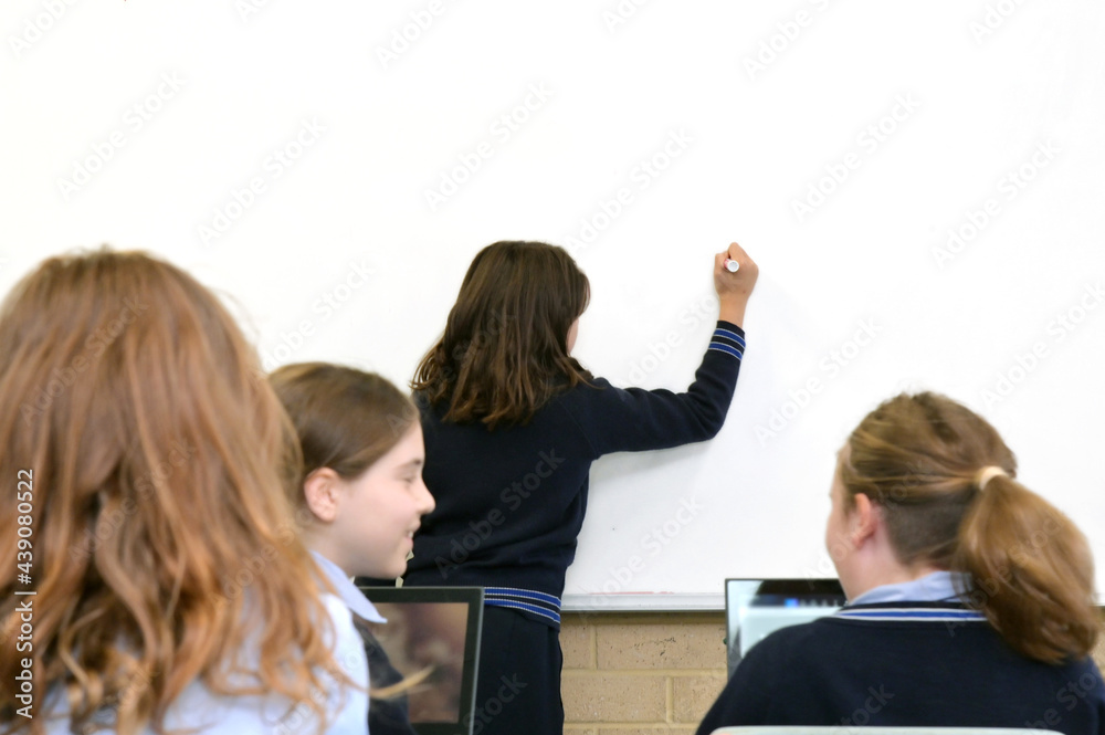 Schoolgirl student writing on a clear whiteboard Stock Photo | Adobe Stock