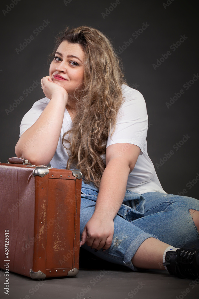 Beautiful fat woman in denim clothes with an old retro suitcase on a ...