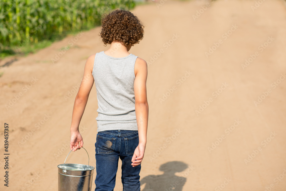 Boy carrying bucket of produce Stock Photo | Adobe Stock