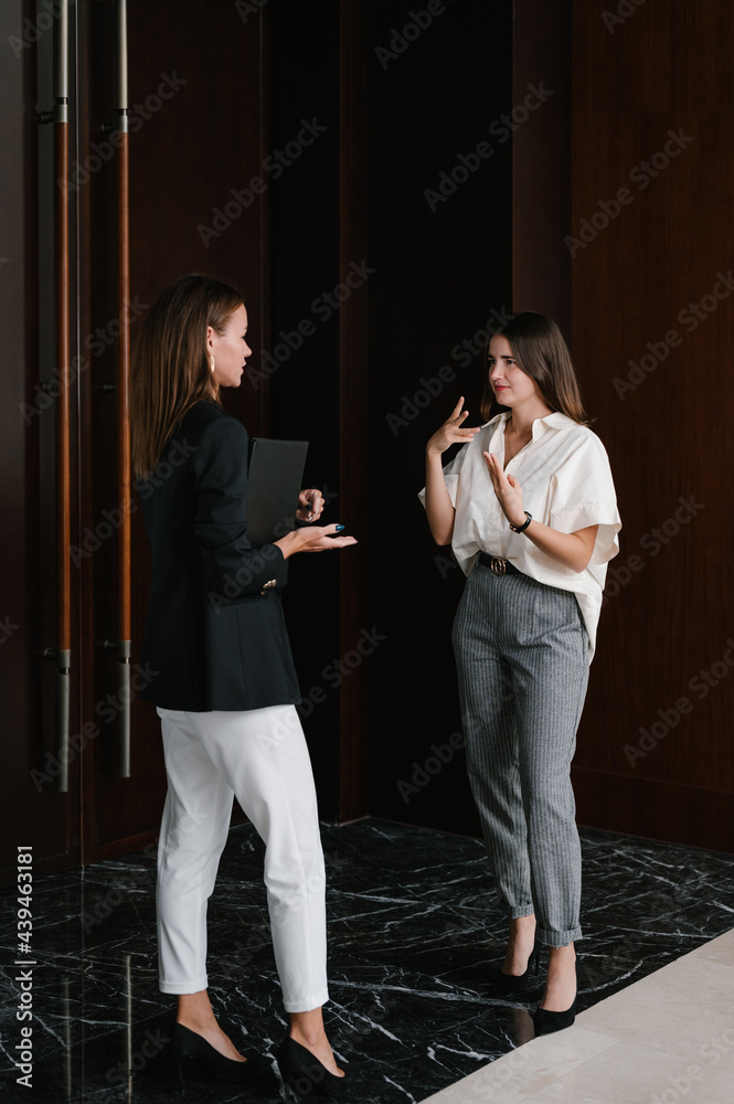 Deaf businesswomen using sign language in hallway Stock Photo | Adobe Stock
