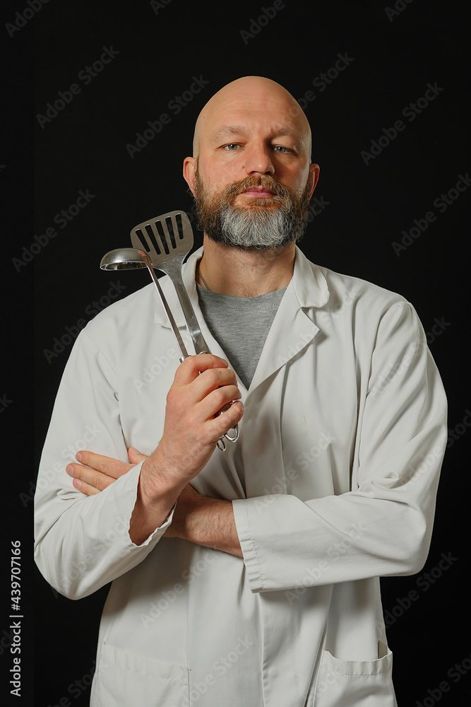 Portrait of handsome chef cook on a black background. The model is in ...