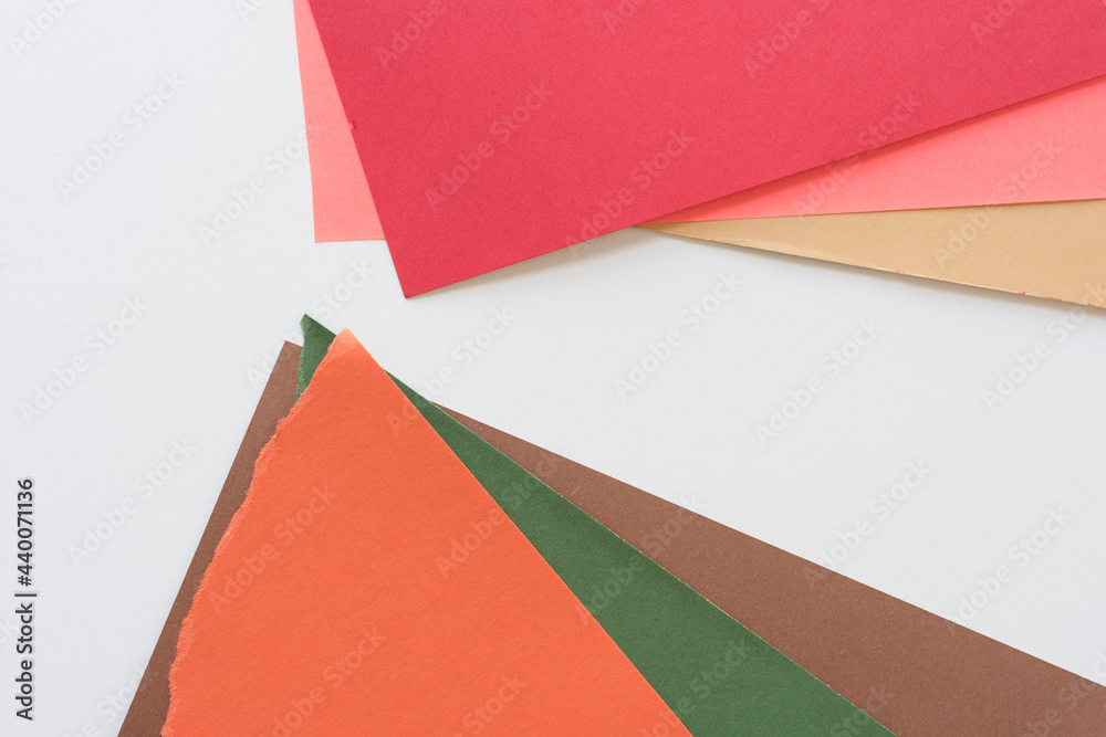overlapping torn orange green and brown paper and straight edged pink ...