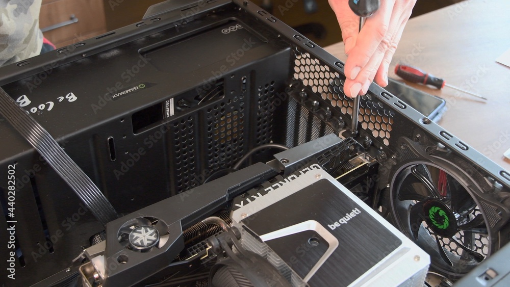 Hands with screwdriver assemble CPU cooler and NVidia GeForce RTX 3080 ...