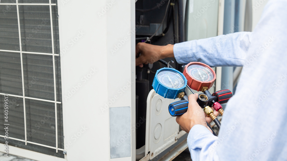 Air repair mechanic using measuring equipment for filling industrial ...