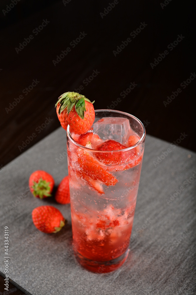 iced strawberry fruit cooler mocktail / kombucha in glass on bar counter dark night background ...