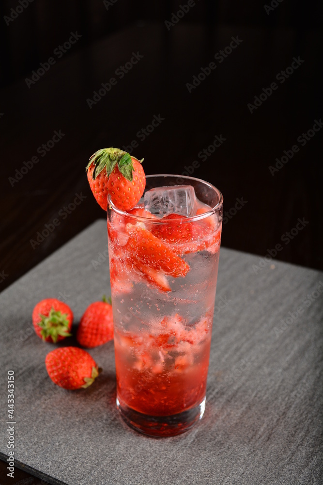 iced strawberry fruit cooler mocktail / kombucha in glass on bar counter dark night background ...
