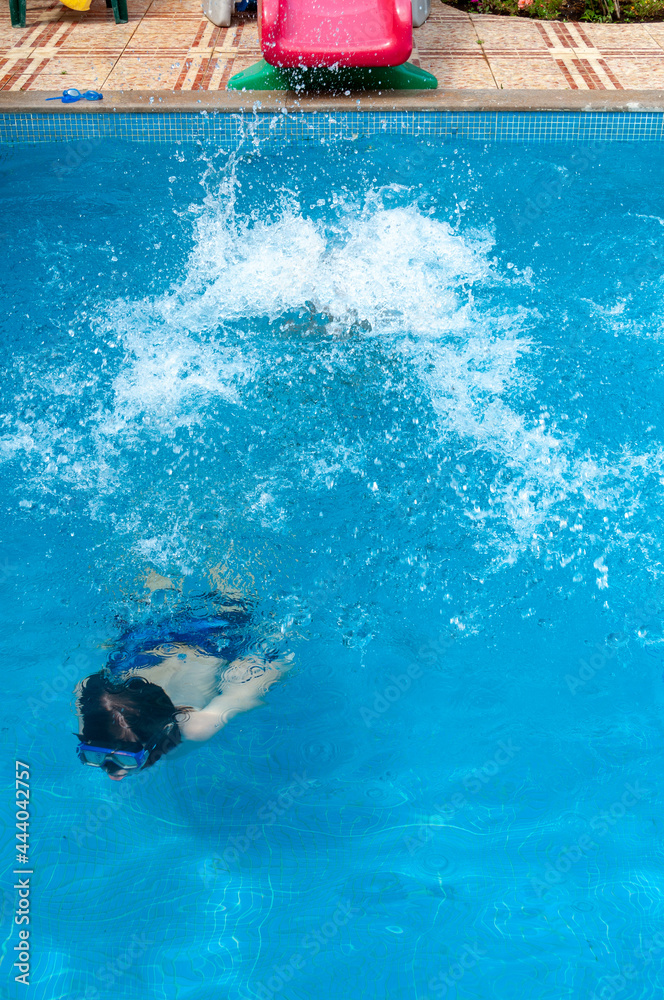 Child jumping from slide into the swimming pool, with big water ...