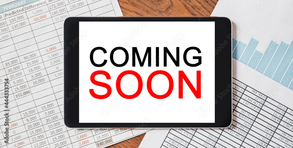 Tablet with text COMING SOON on your desktop with documents, reports ...