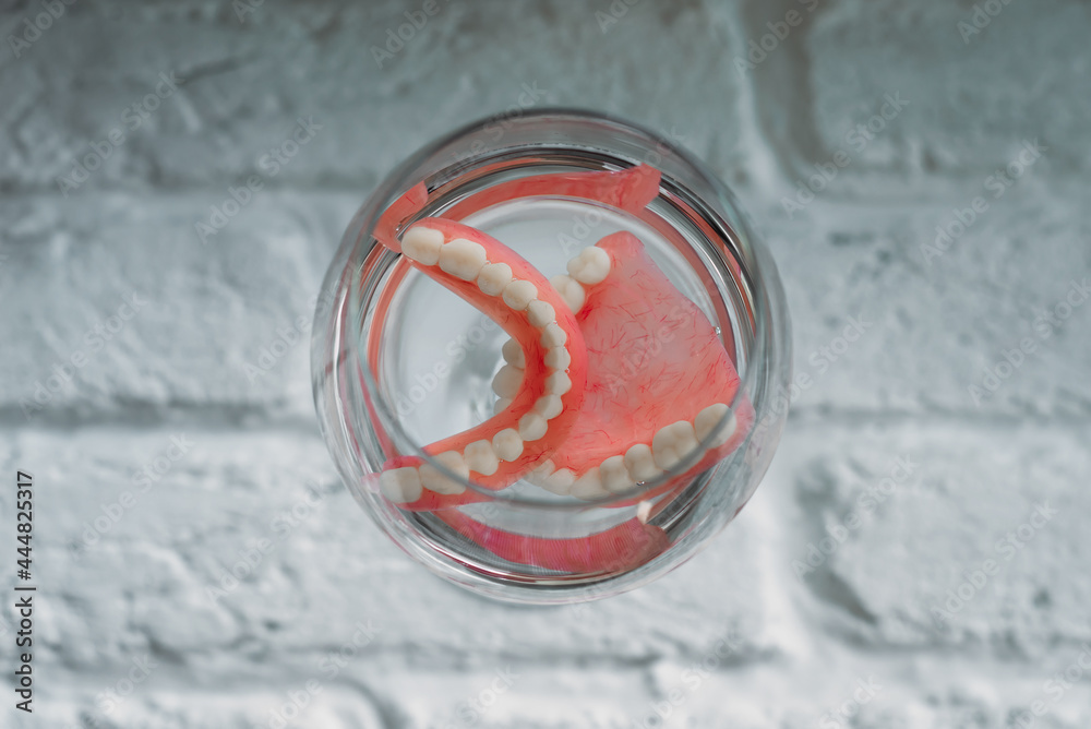 A denture in a glass of water. Dental prosthesis care. Full removable ...
