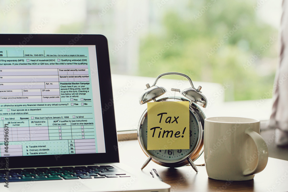 Tax time concept. tax time on a post-it on alarm clock and Individual ...
