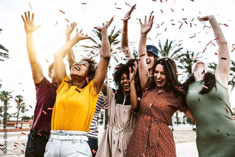 Group of friends enjoying party throwing confetti in the air ...