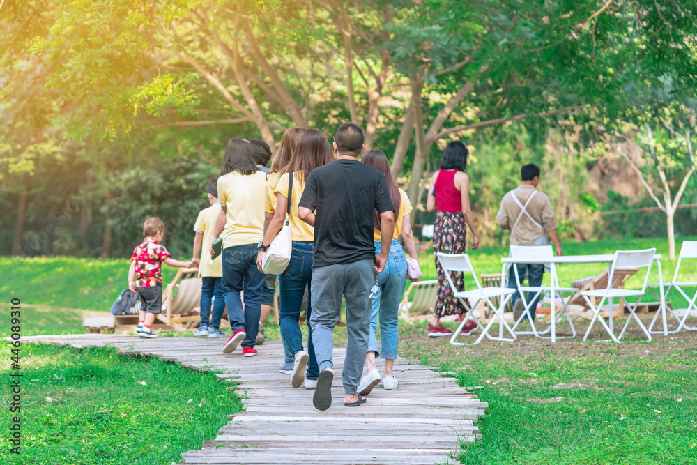 Back view of Asian man walking on pathway through green garden. Group ...