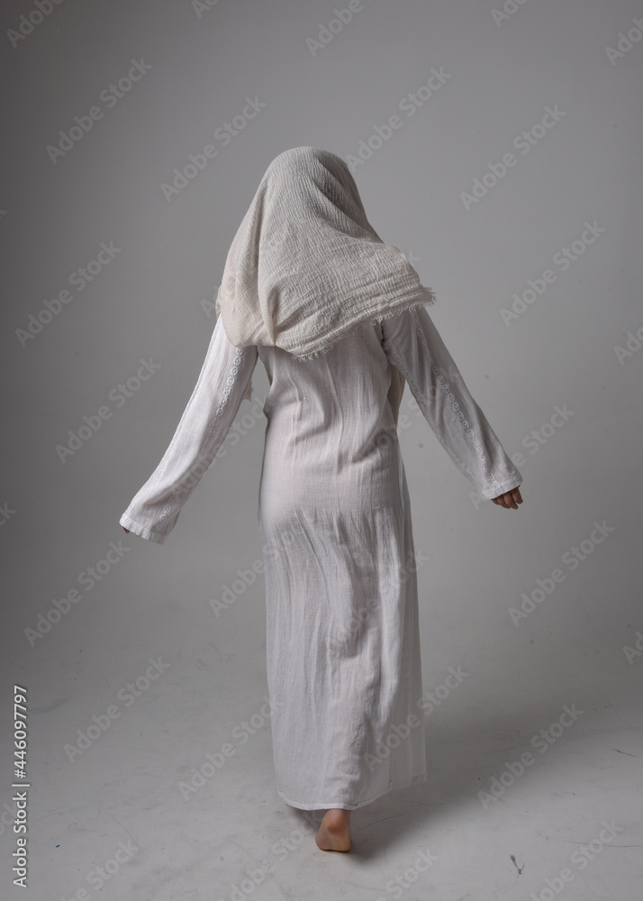 Full length portrait of young woman wearing classical white gown and a ...